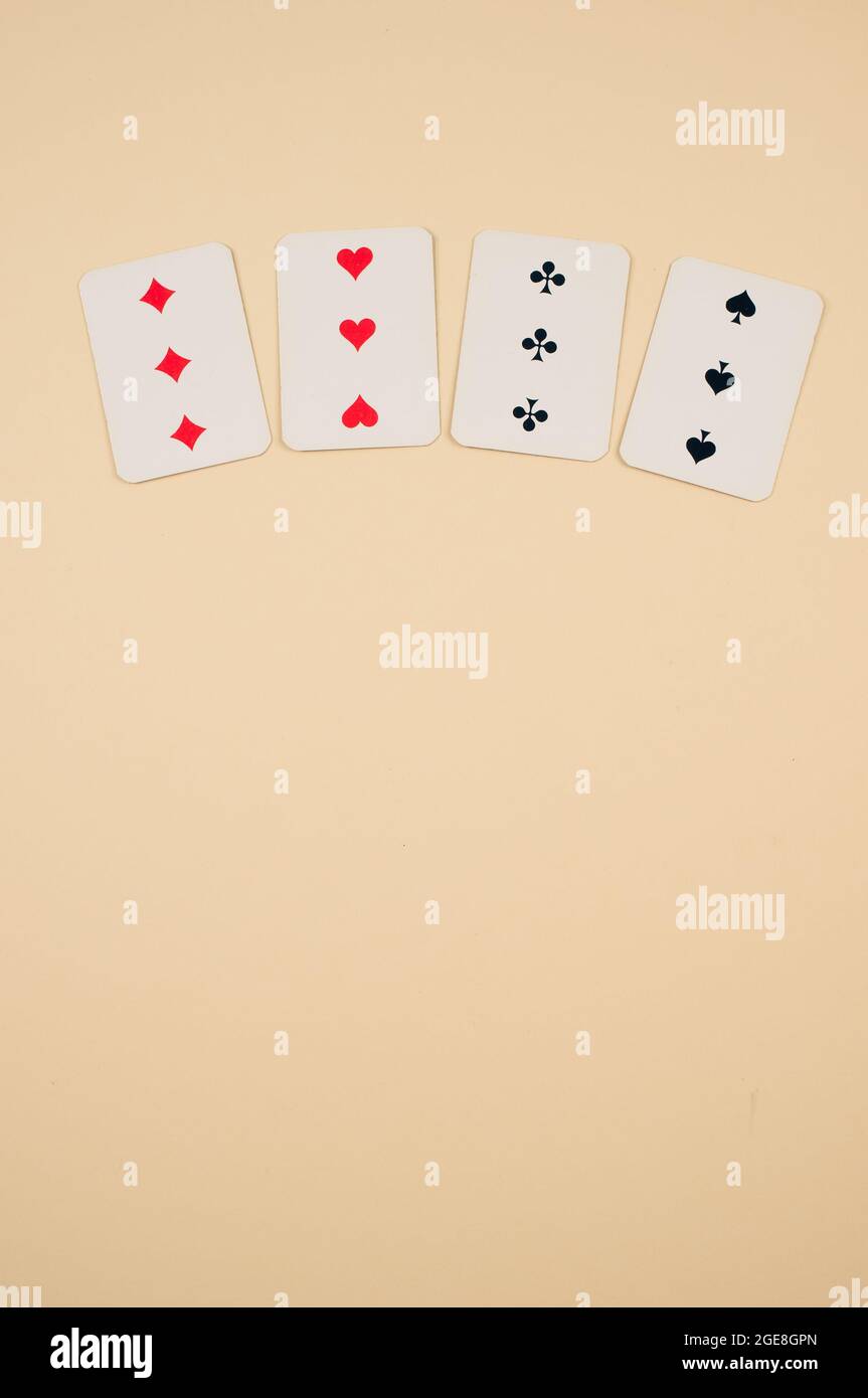 3 of diamonds, hearts, clubs, and spades poker cards on a beige ...