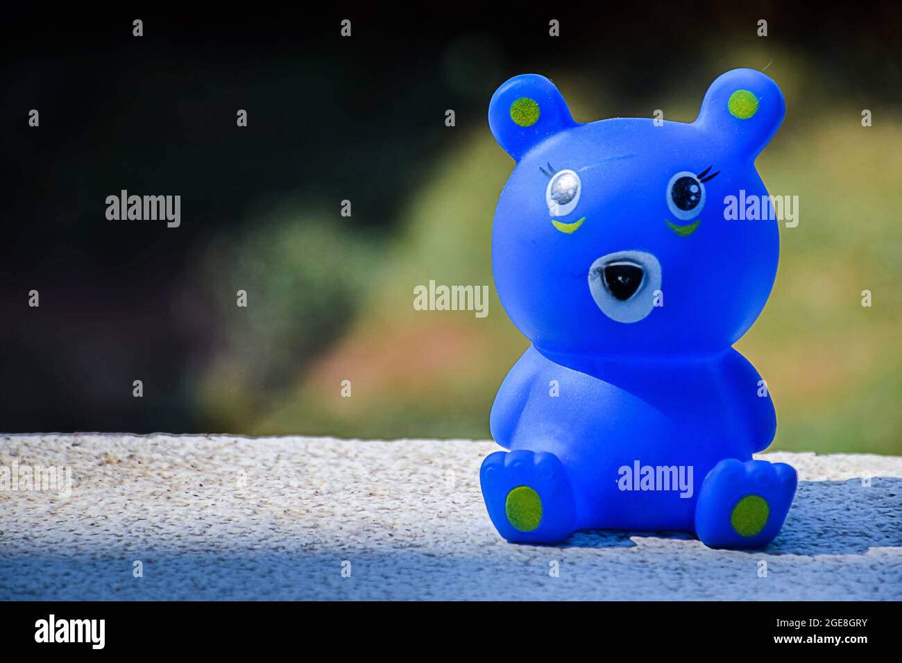 Cute blue bear plastic toy on a concrete surface under sunlight Stock ...