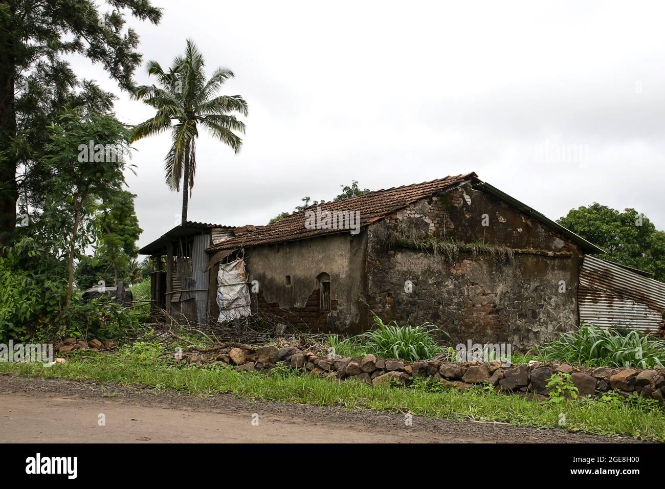 Old damaged brick house with a pyramid-shaped roof in Kolhapur ...