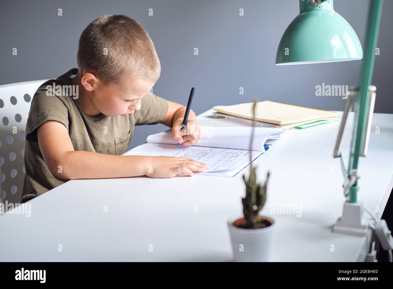 The schoolboy sitting at the table and doing schoolwork at home ...