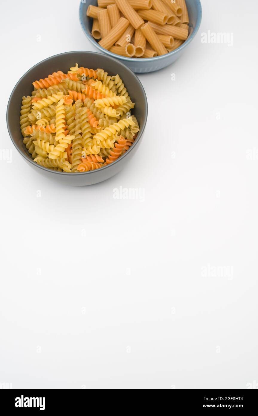 Vertical shot of tri-color rotini and rigatoni pasta on a bowl isolated ...