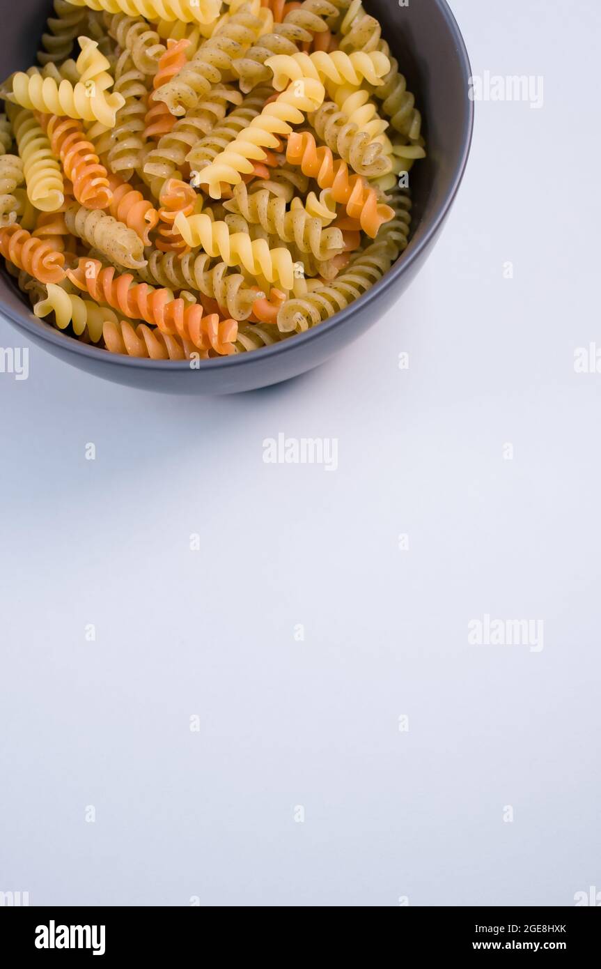 Vertical shot of tri-color rotini pasta on a bowl isolated on white ...