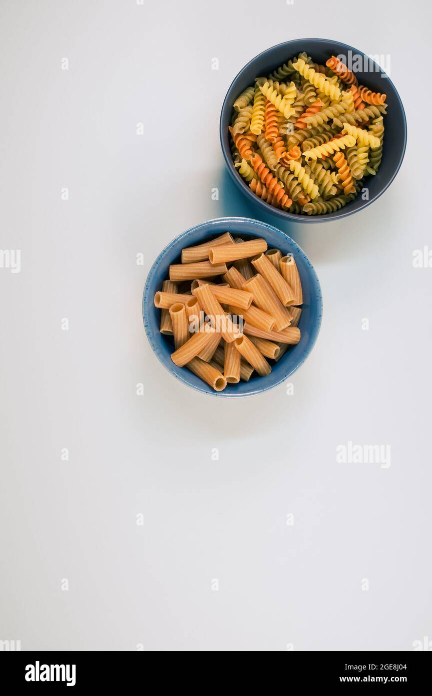 Vertical sof tri-color rotini and rigatoni pasta on bowls isolated on ...