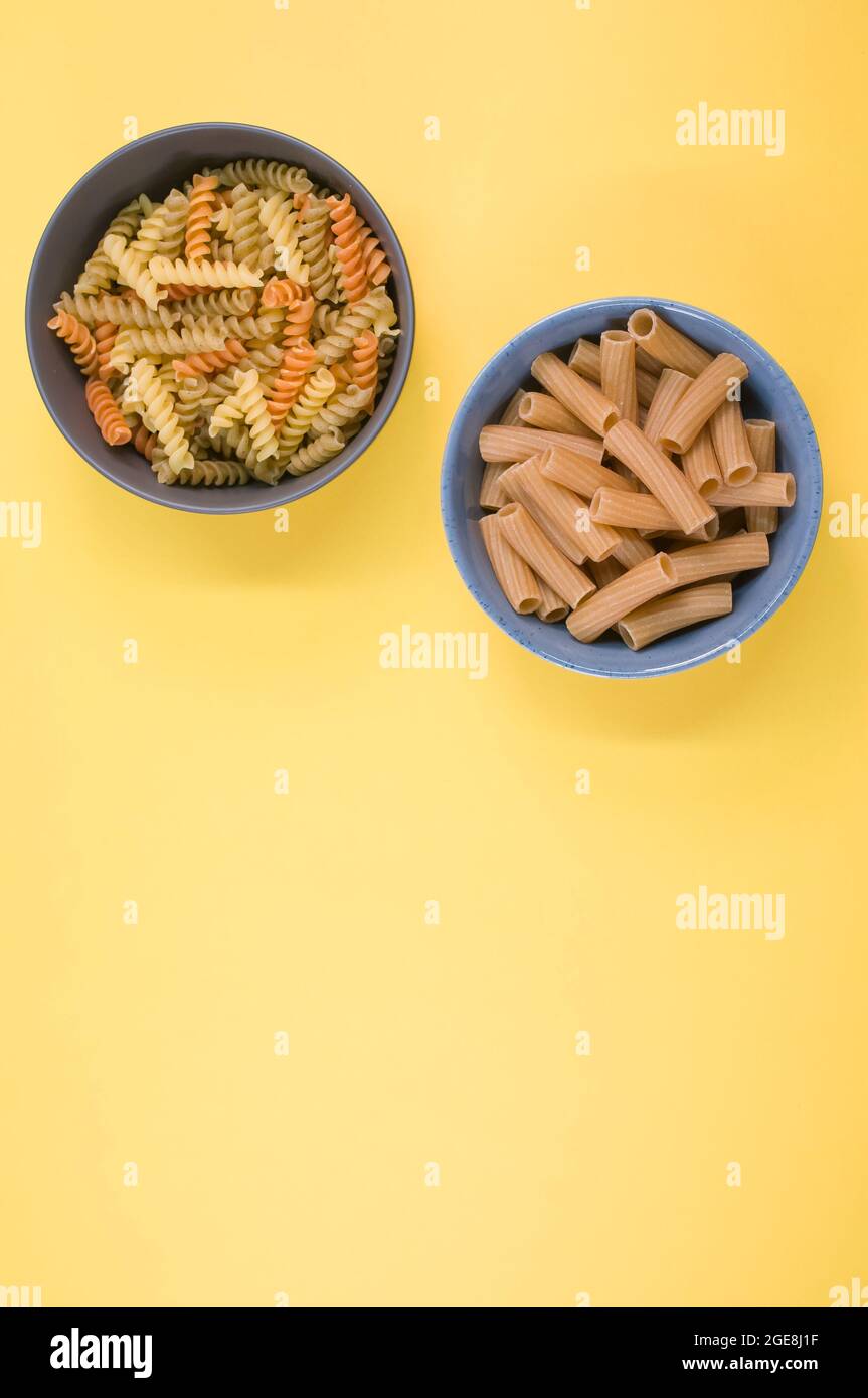 Vertical shot of tri-color rotini and rigatoni pasta on a bowl isolated ...
