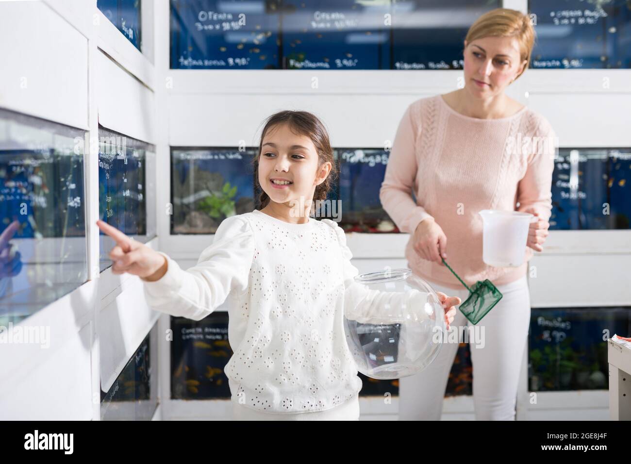 Girl with mother choosing aquarium fish Stock Photo - Alamy