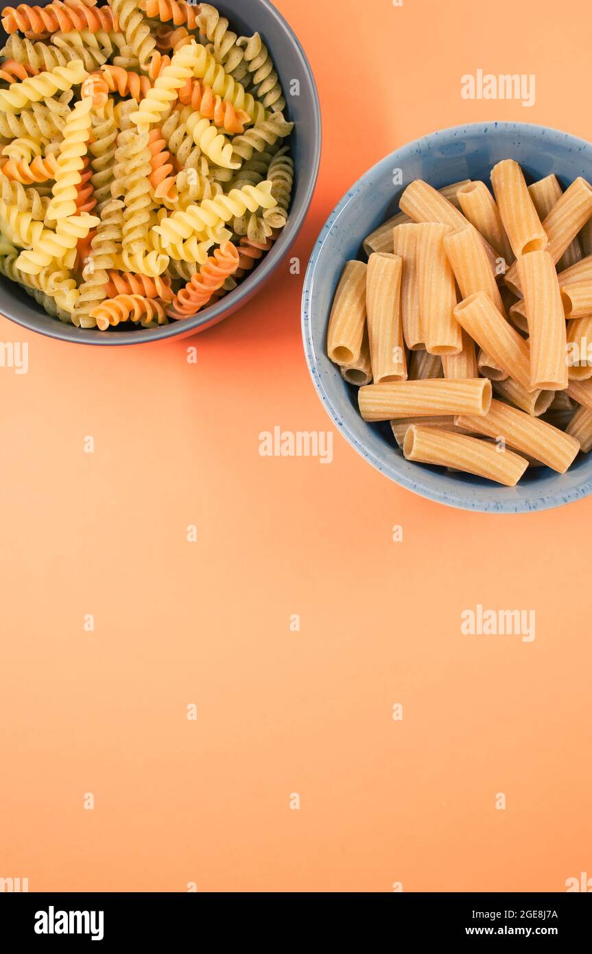 Vertical shot of tri-color rotini and rigatoni pasta on a bowl isolated ...