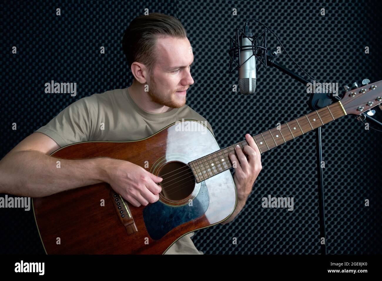 Young caucasian man sings while playing an acoustic guitar in front of ...