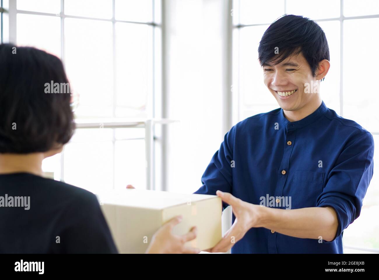 The delivery staff in a black uniform handed the box to the young ...