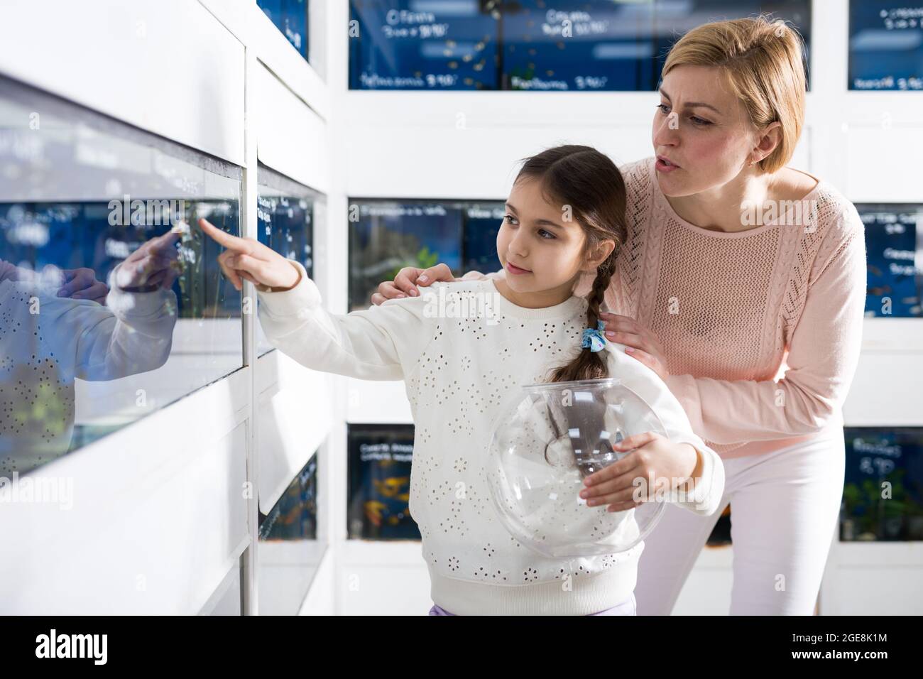 Cute girl with her mother customer buying tropical fish Stock Photo - Alamy