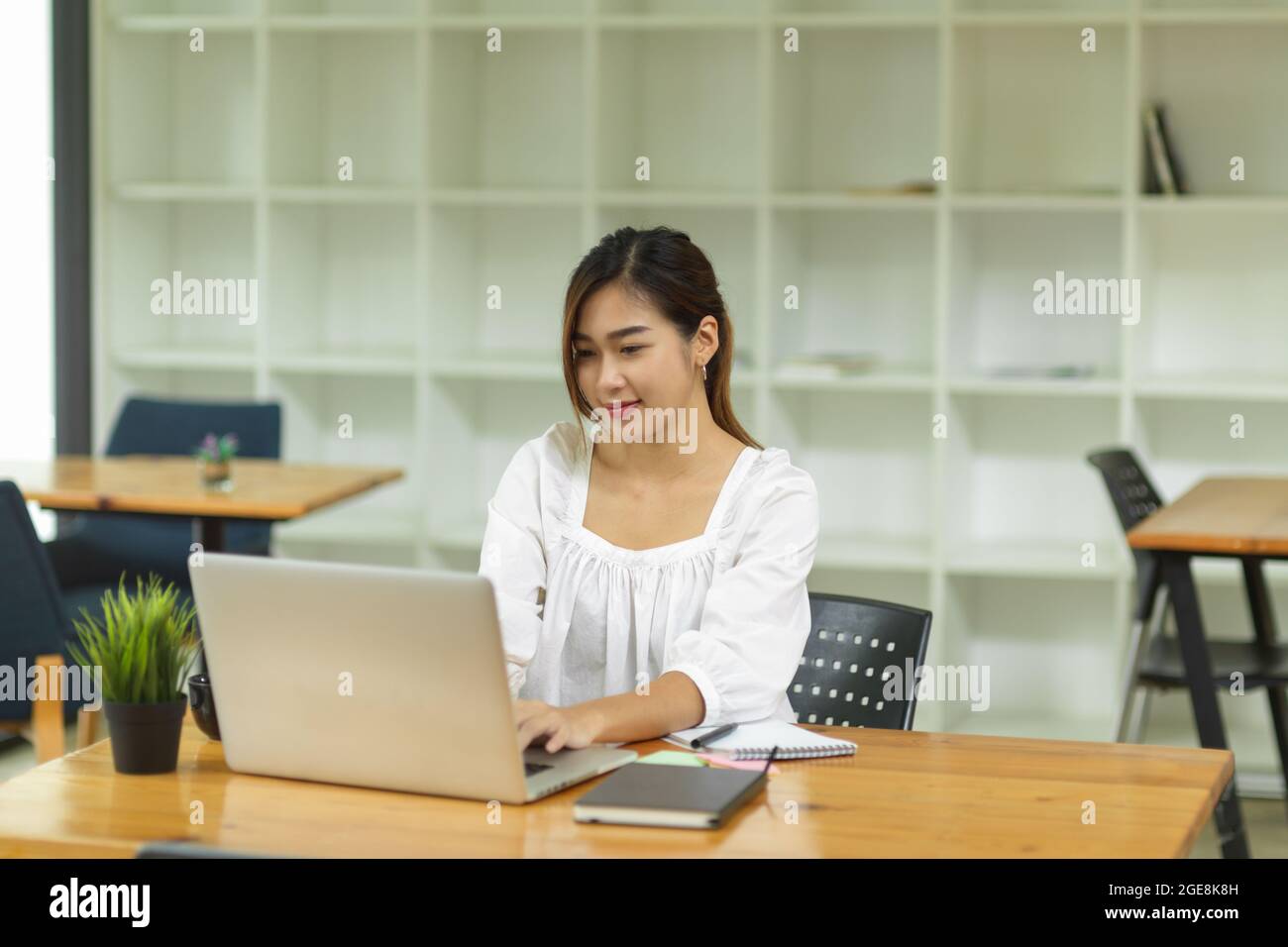 Elegant female college student sitting and using laptop computer in ...