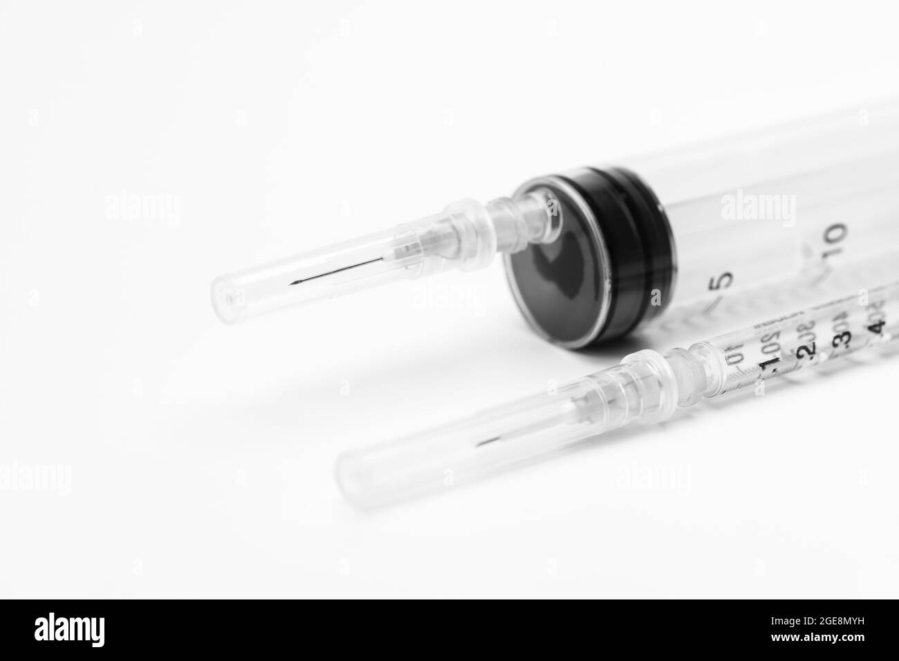 Two medical syringes for vaccine injection on white background. Close ...