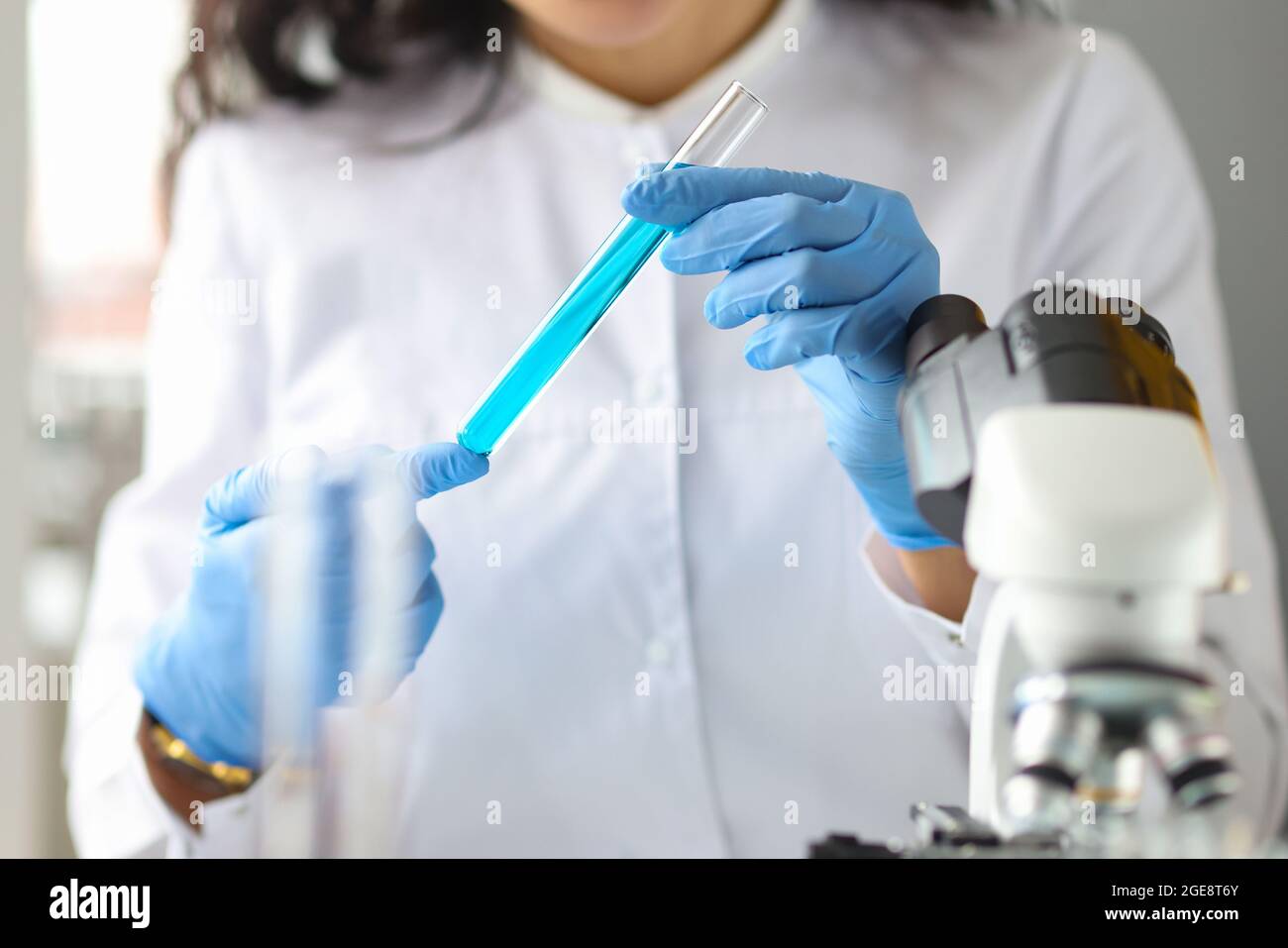 Scientist hands in gloves holds test tube with blue liquid in ...