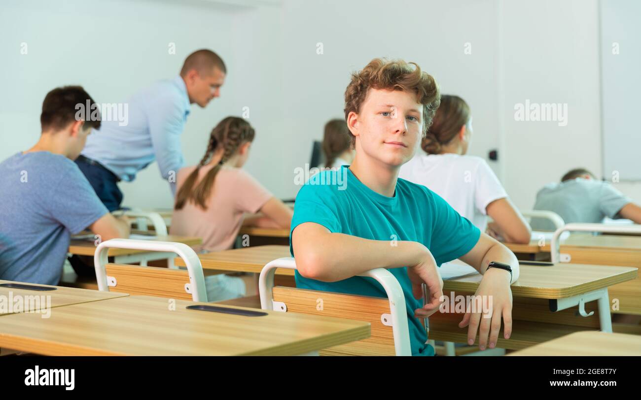 Smiling teen schoolboy sitting at desk in classroom during lesson Stock ...