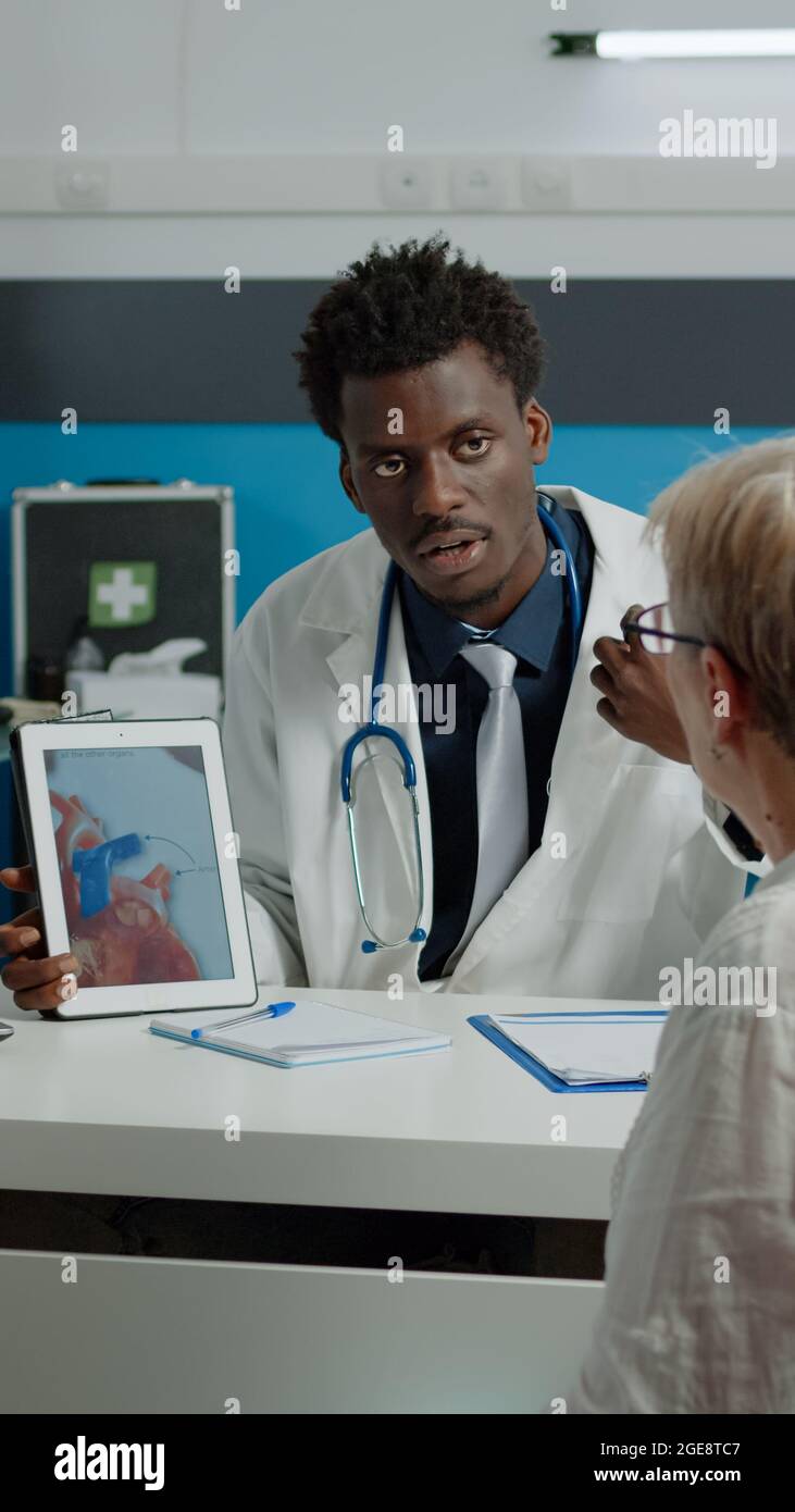 Healthcare specialist explaining cardiogram on tablet display to old ...