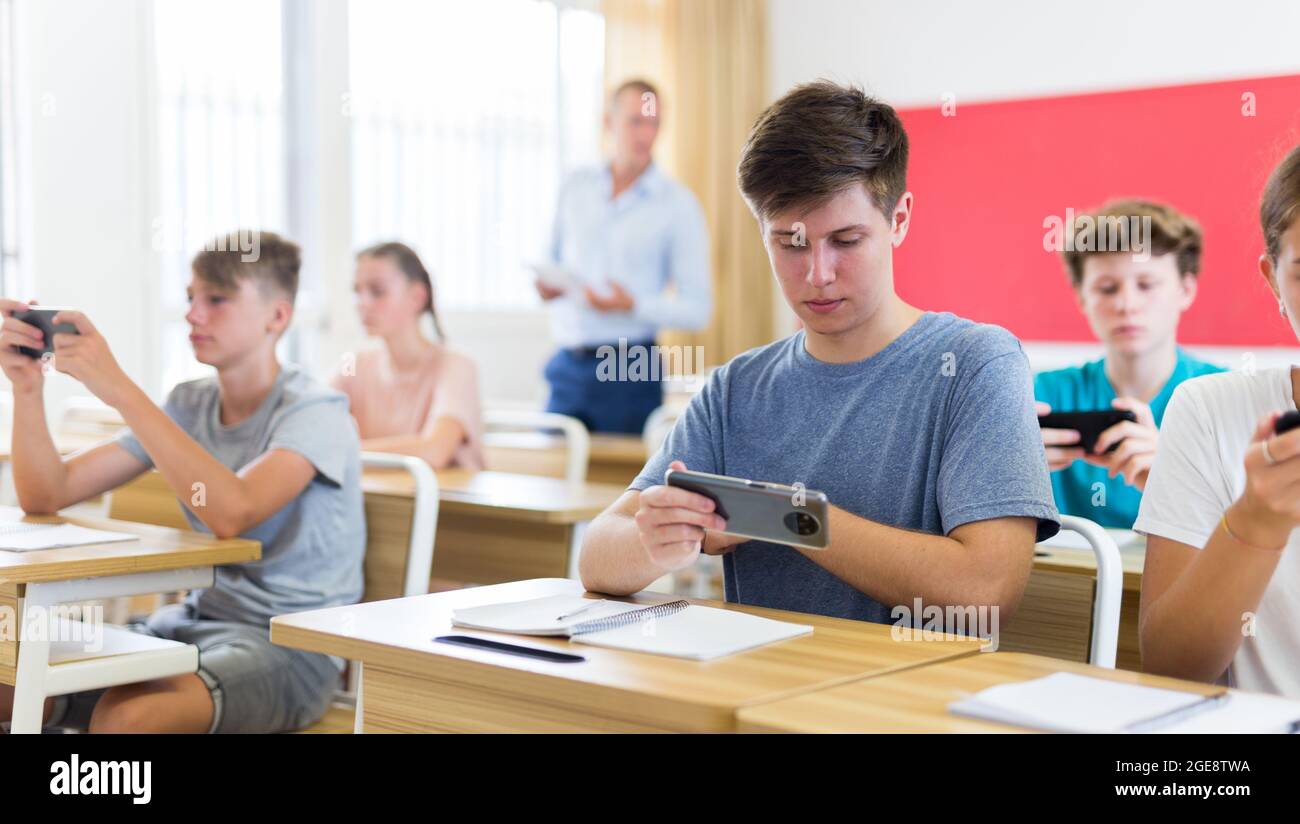 Young students with smartphones sitting in class room Stock Photo - Alamy