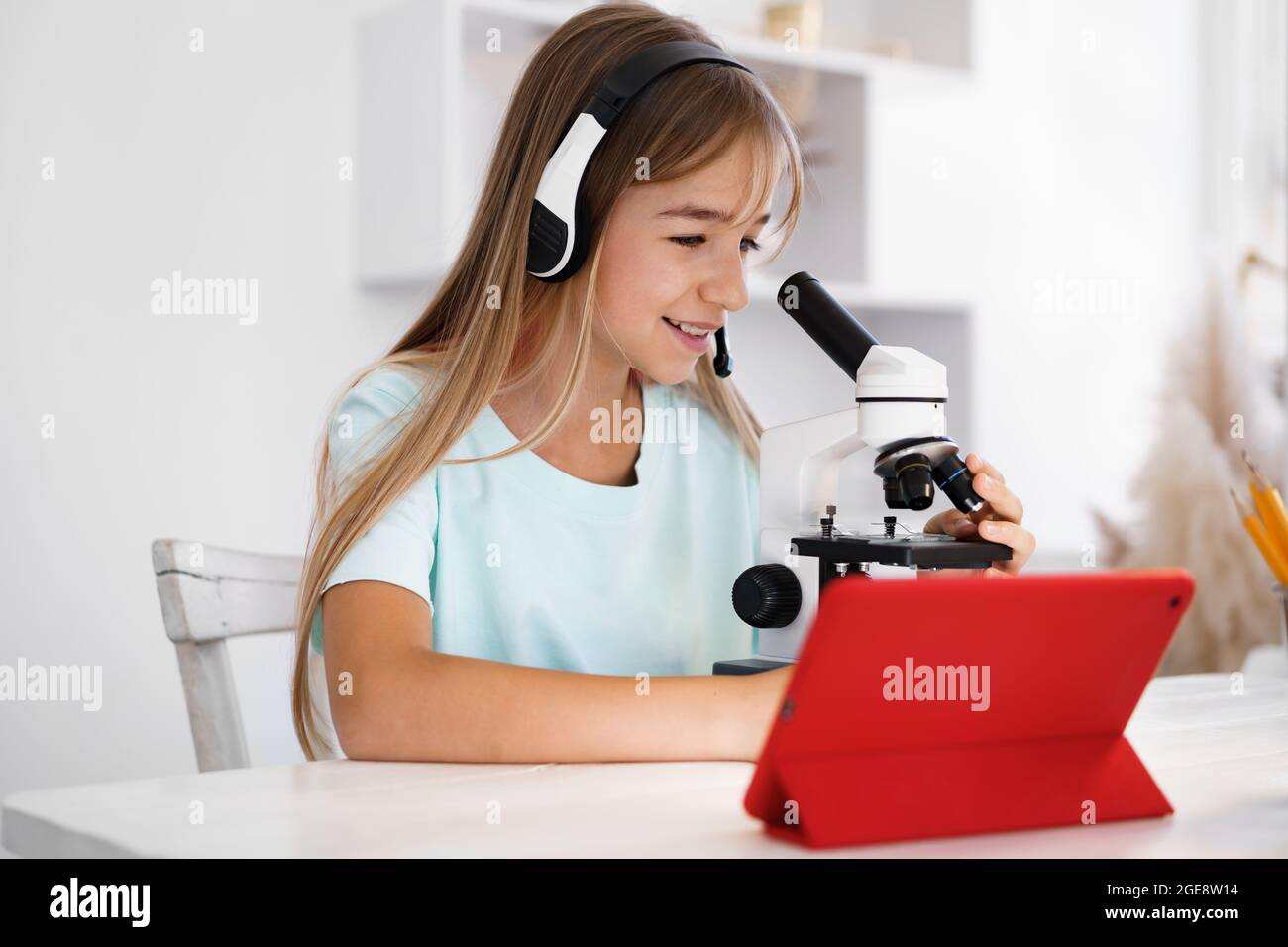 Young girl using microscope during online lesson education at home ...