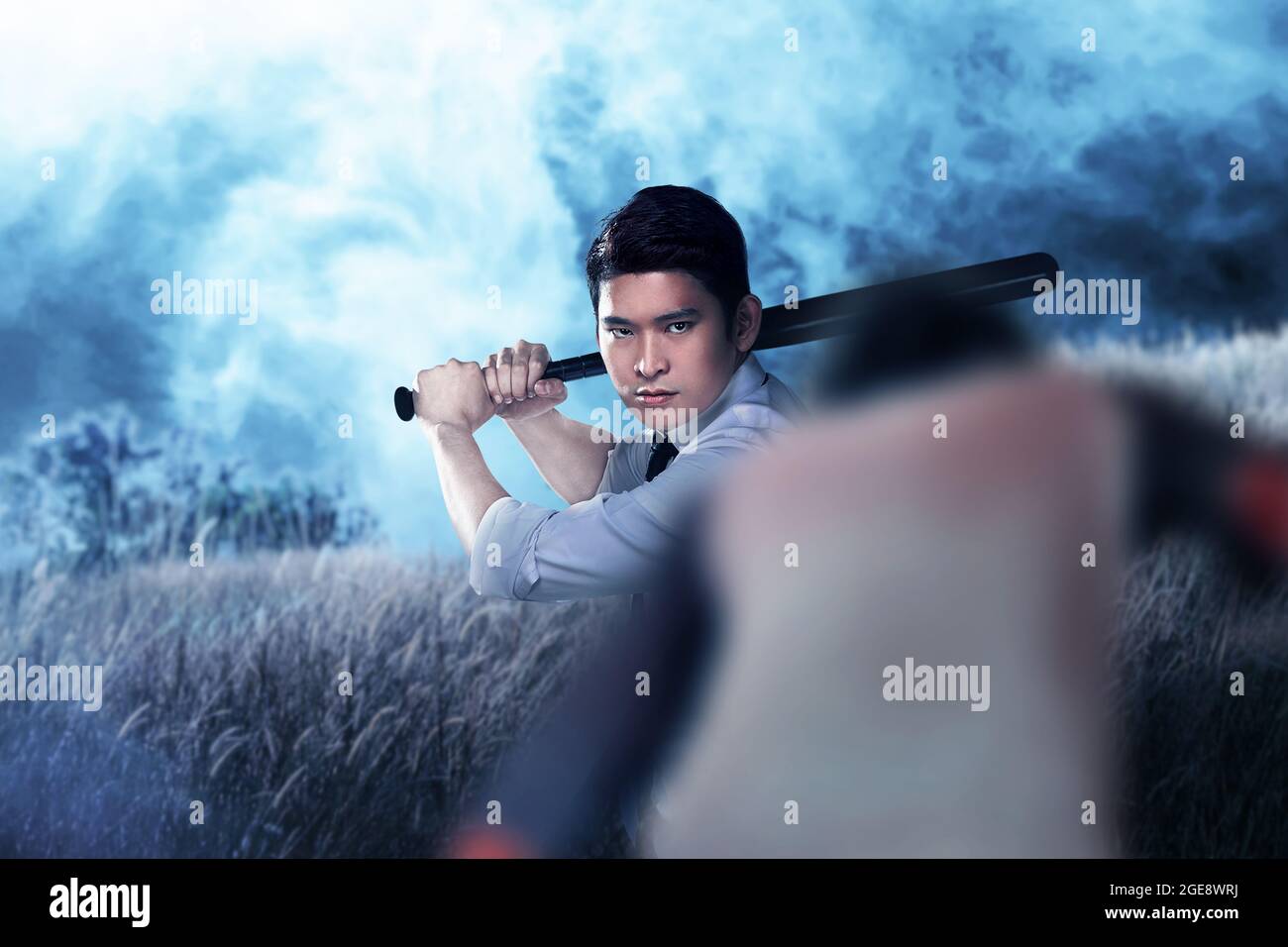 Asian man standing with a baseball bat in his hand ready to attack ...