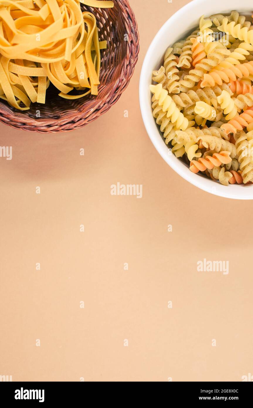 Vertical shot of tri-color rotini and fettuccine pasta on a bowl ...