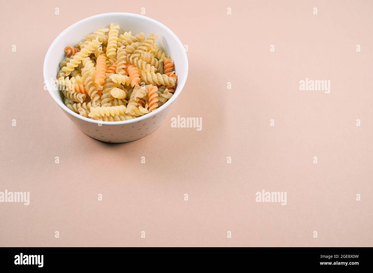 Top view of uncooked tri-color rotini pasta on a bowl isolated on brown ...