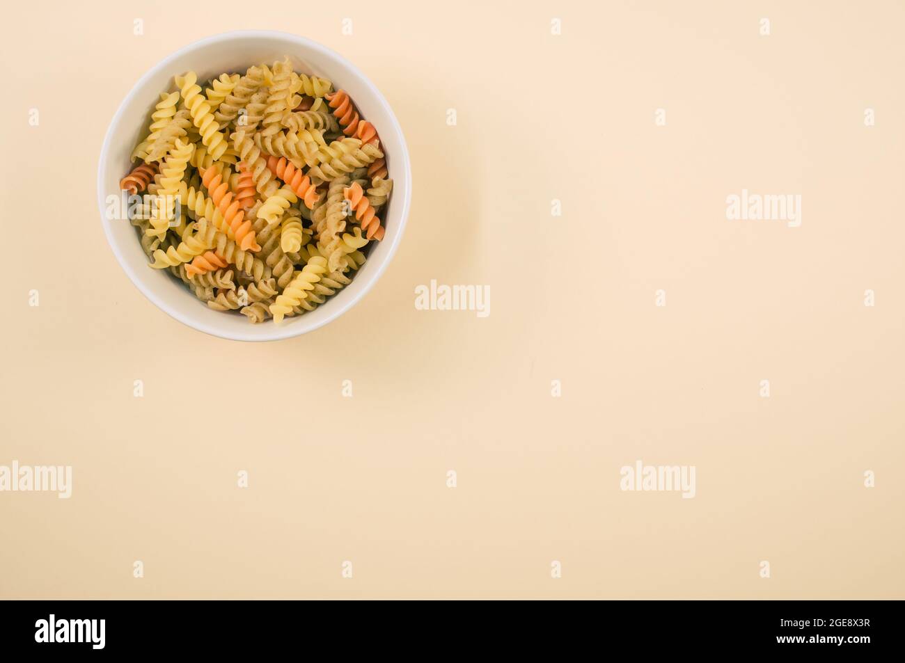 Top view of uncooked tri-color rotini pasta on a bowl isolated on light ...