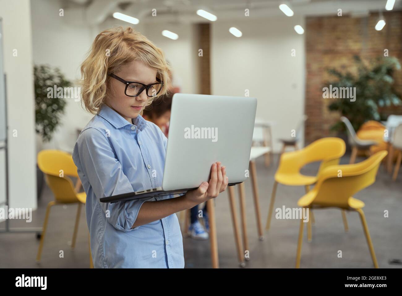 The future of IT. Portrait of little genius boy in glasses holding and ...