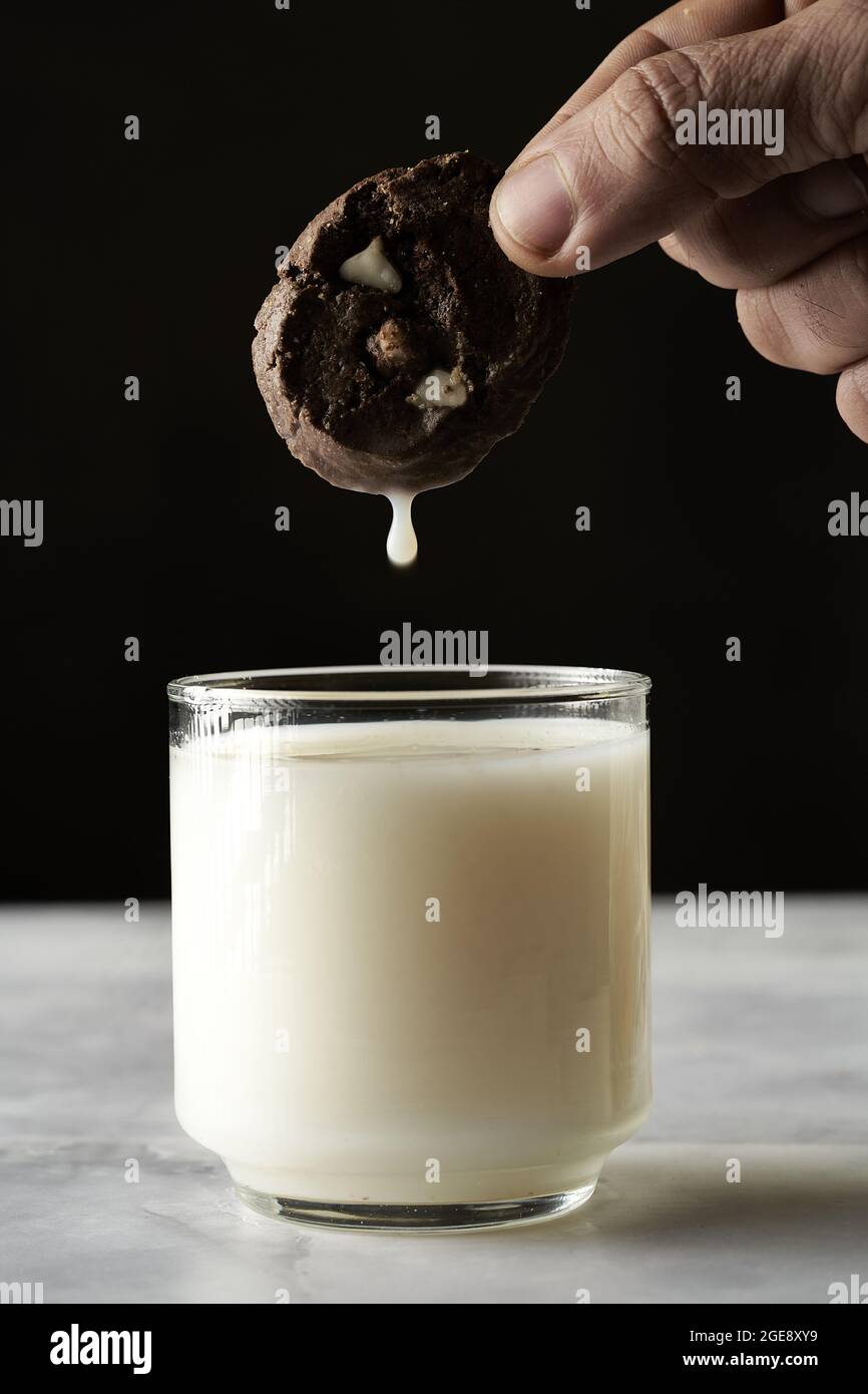 Male hand dipping a cookie in a glass of milk Stock Photo - Alamy