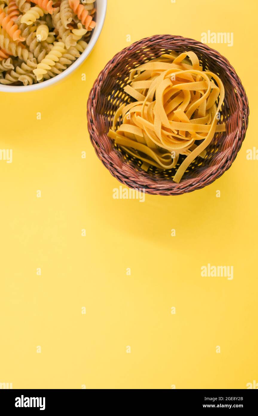 Vertical shot of tri-color rotini and fettuccine pasta on a bowl ...