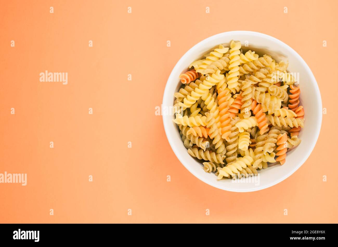 Top view of uncooked tri-color rotini pasta on a bowl isolated on an ...