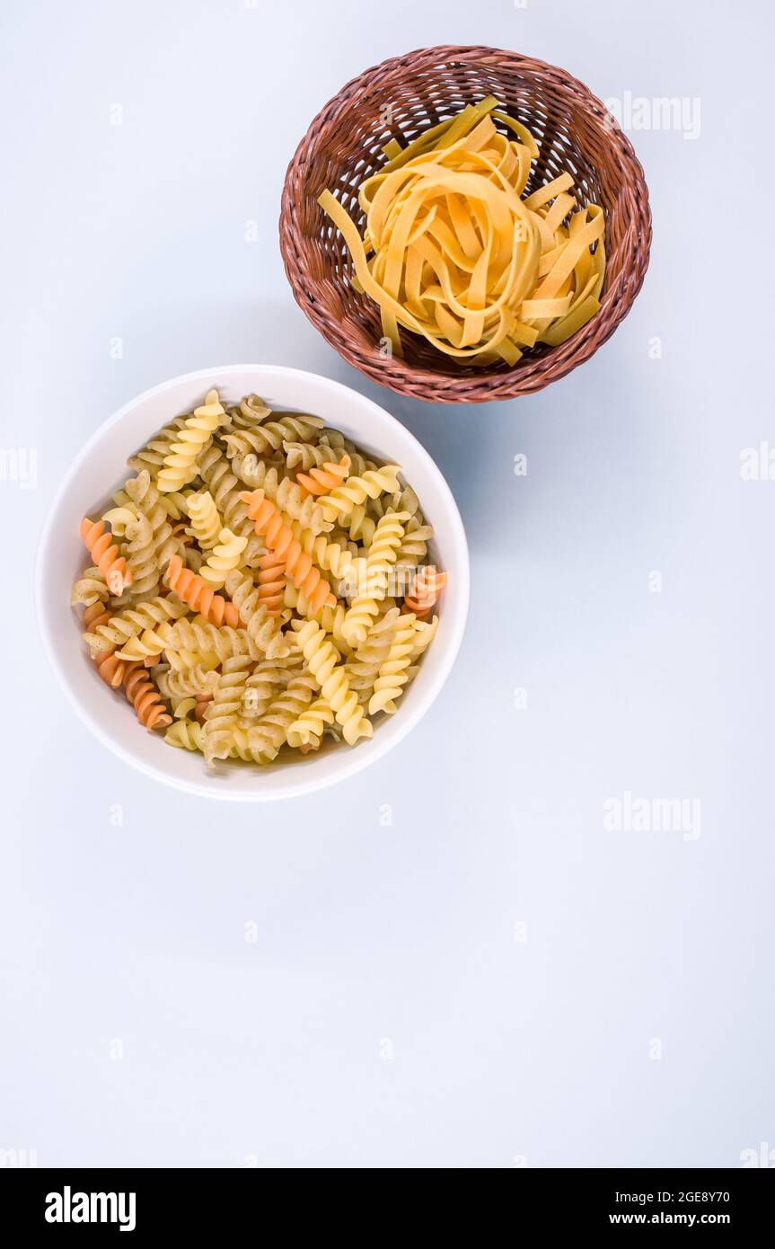 Vertical shot of tri-color rotini and fettuccine pasta on a bowl ...
