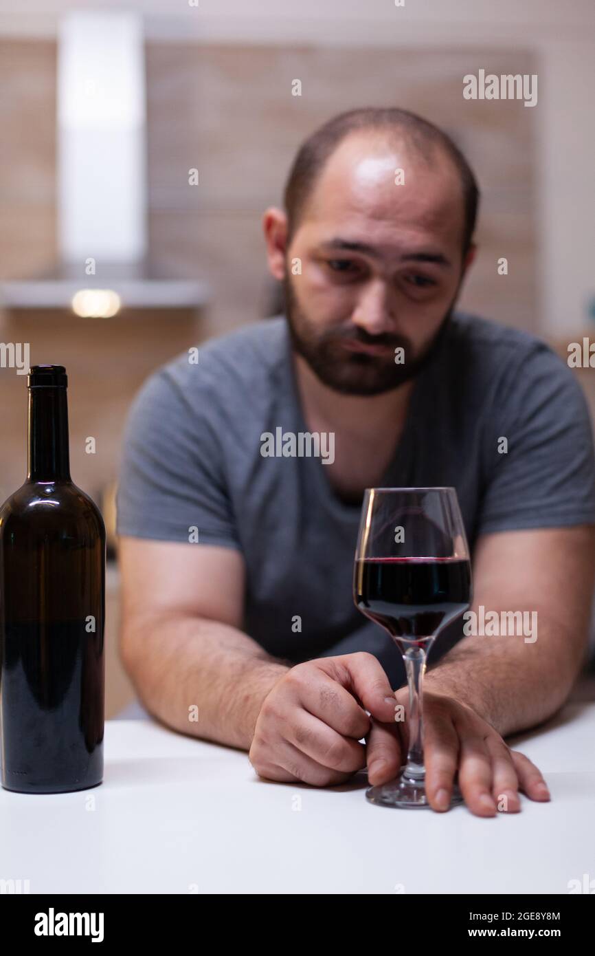 Close up of glass with wine for lonely man in kitchen. Miserable adult ...