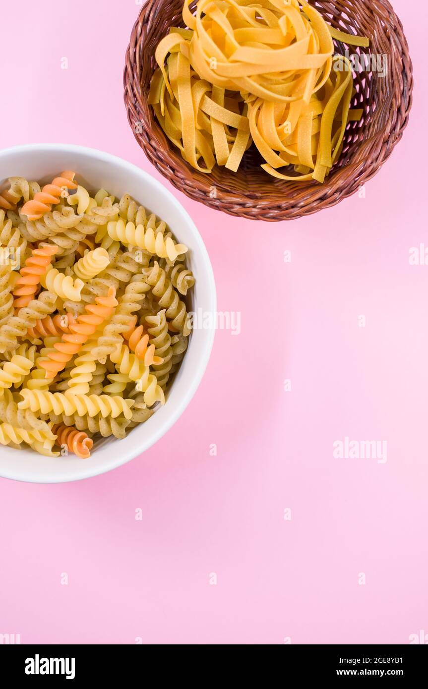 Vertical shot of tri-color rotini and fettuccine pasta on a bowl ...
