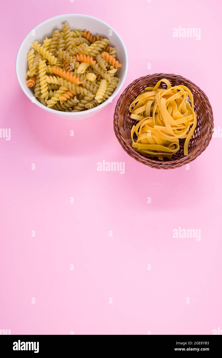Vertical shot of tri-color rotini and fettuccine pasta on a bowl ...