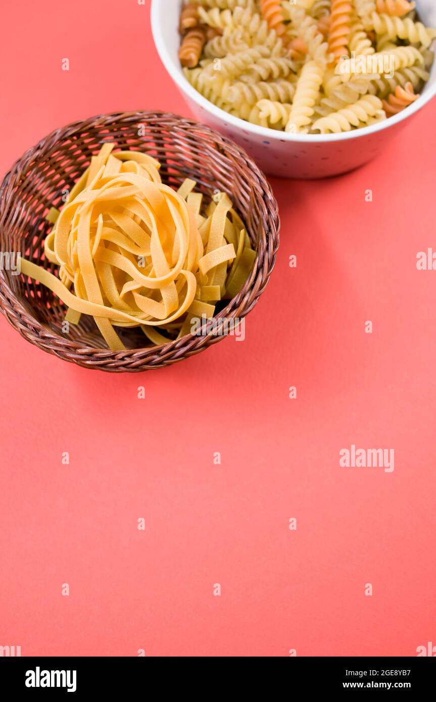 Vertical shot of tri-color rotini and fettuccine pasta on a bowl ...