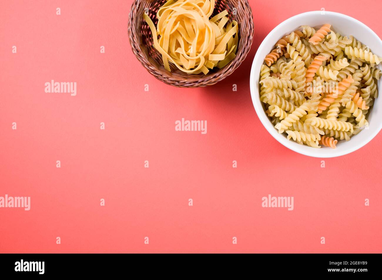 Top view of uncooked tri-color rotini and fettuccine pasta on a bowl ...
