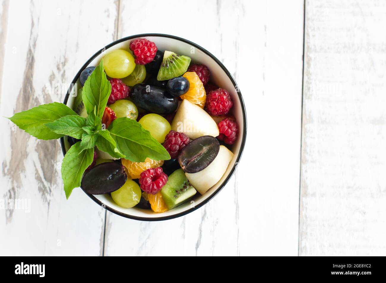 healthy breakfast with a mix of fruits and berries in a bowl on a white ...