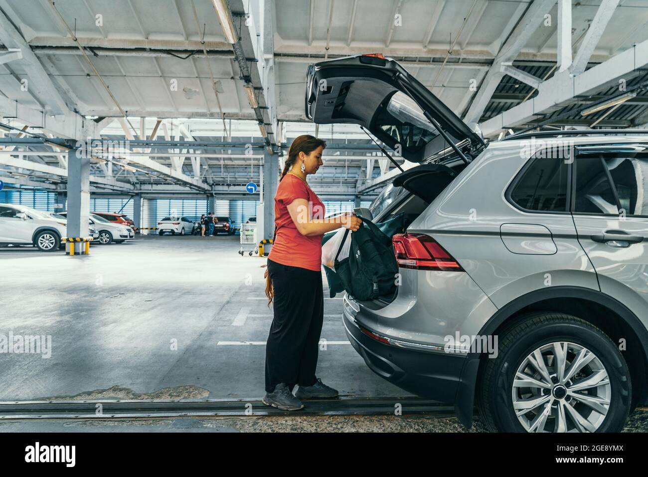 Girl puts shopping bags in trunk of car in shopping mall parking lot ...