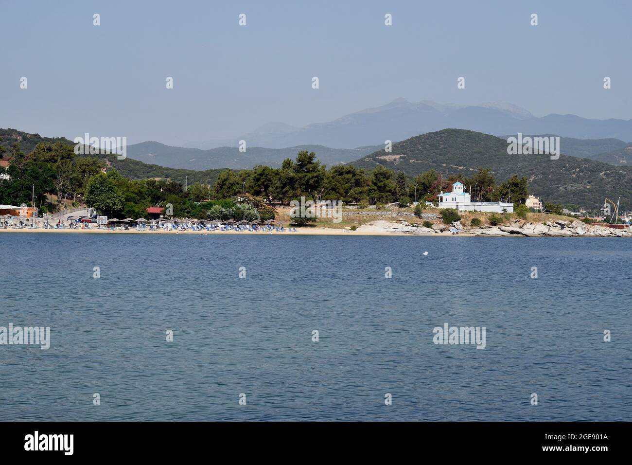 Greece, people on beach and orthodox chapel on Hill in Nea Iraklitsa ...