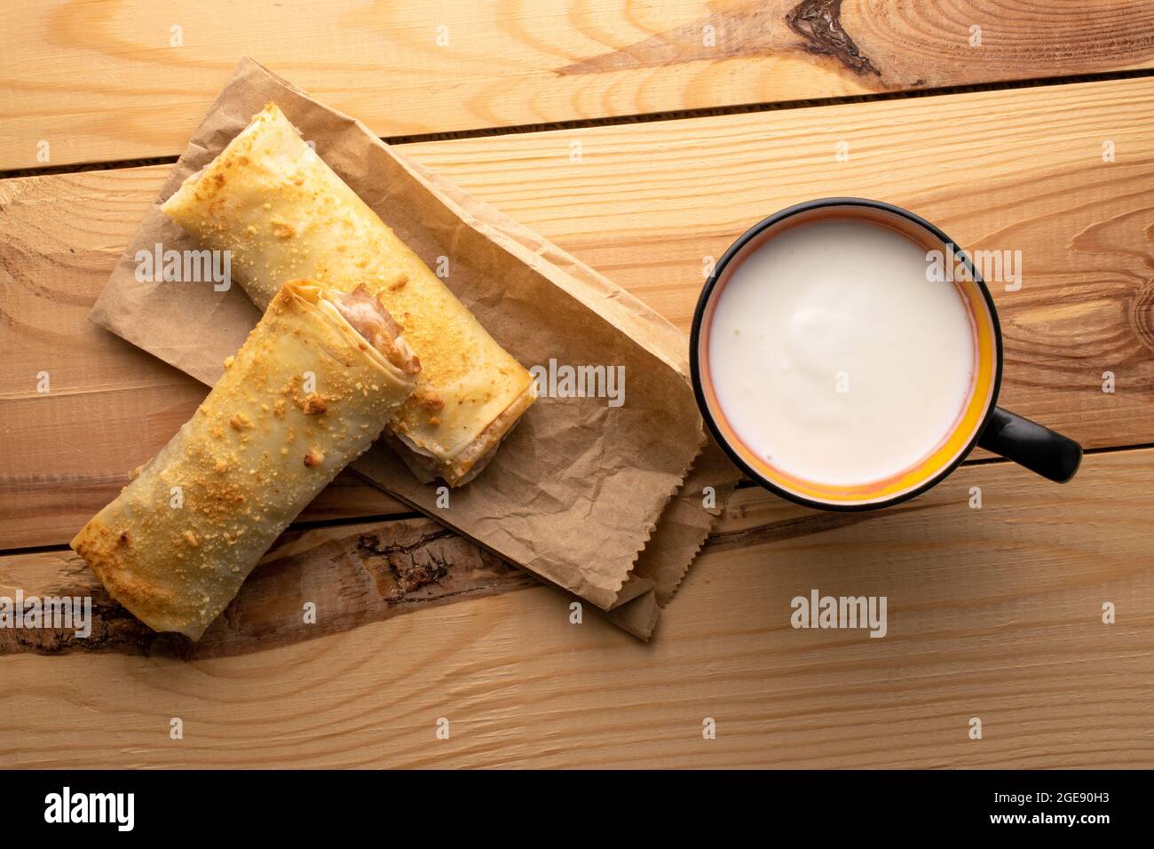 Two mini strudel with an apple on a paper bag with a cup of kefir ...