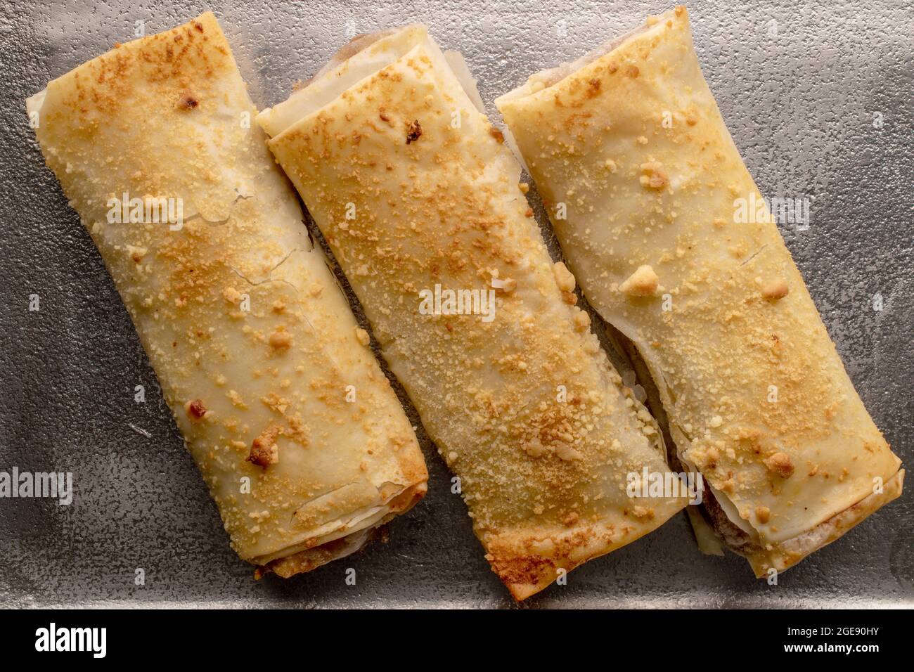 Three mini strudel with an apple, close-up, on a metal tray, top view ...