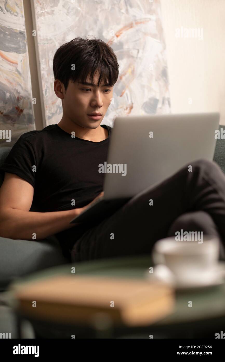 Young Chinese man using laptop at home Stock Photo - Alamy