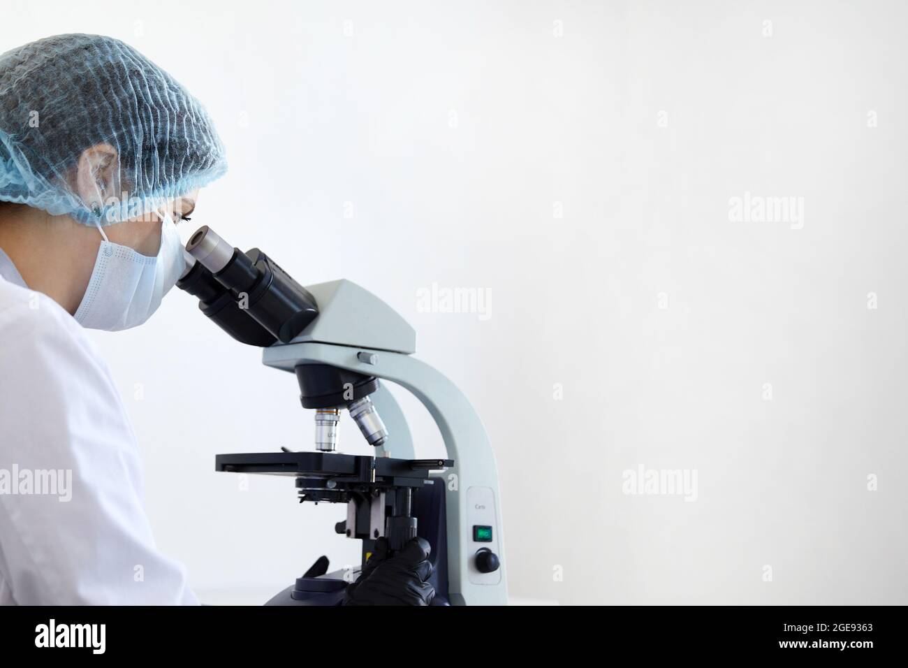 Female scientist looking through microscope in modern chemical ...