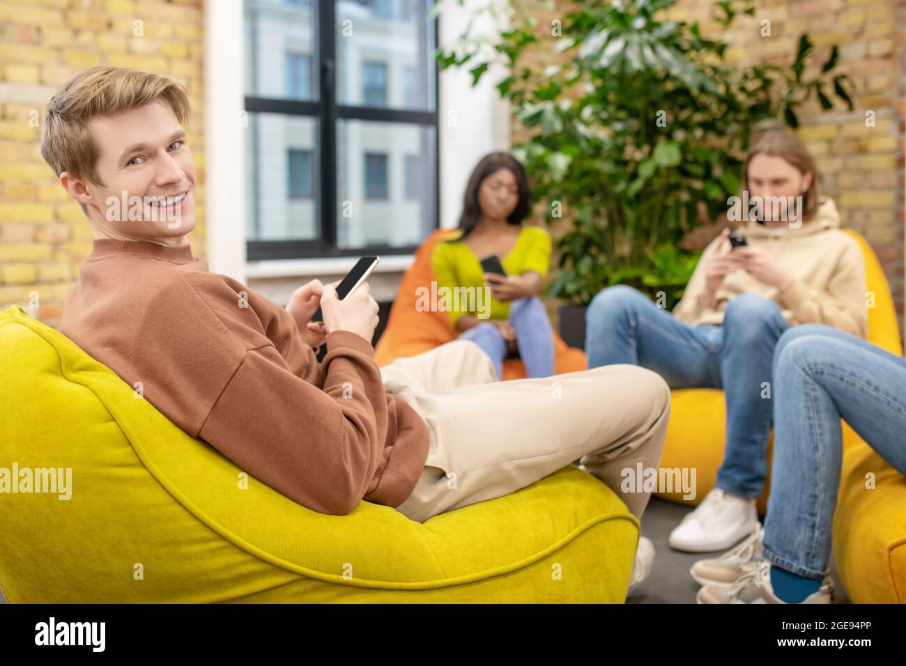 Young people sitting together and looking interested Stock Photo - Alamy