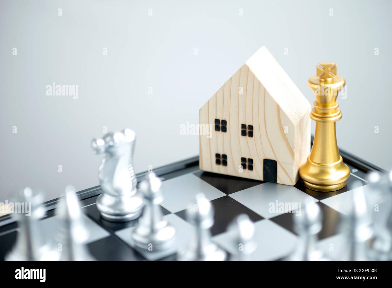 Wooden house model with a gold king chess on a chessboard with silver ...