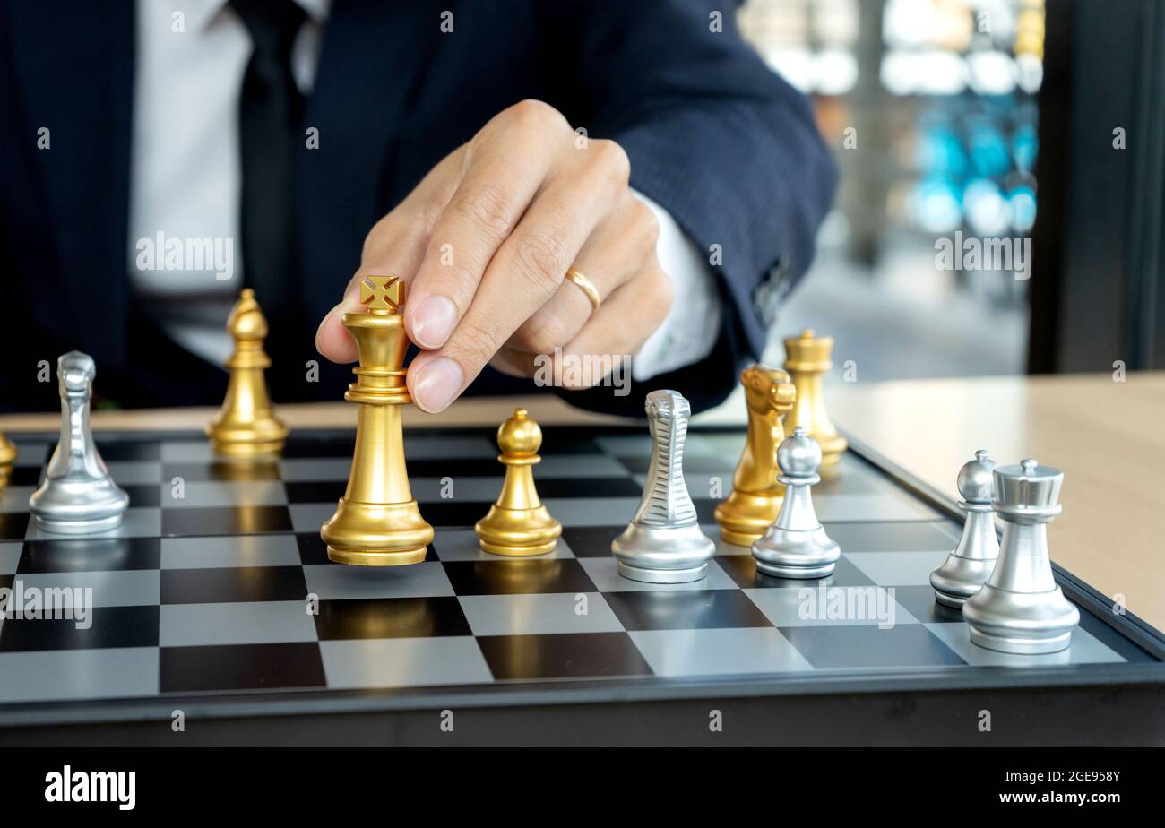 A business man in a suit is holding a chess king figure on the board ...