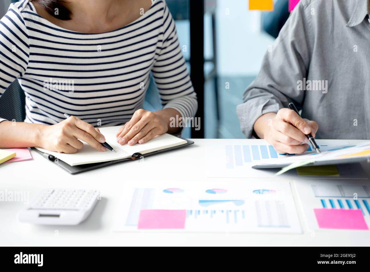 Business women and business men sit on a notebook at work on their desk ...