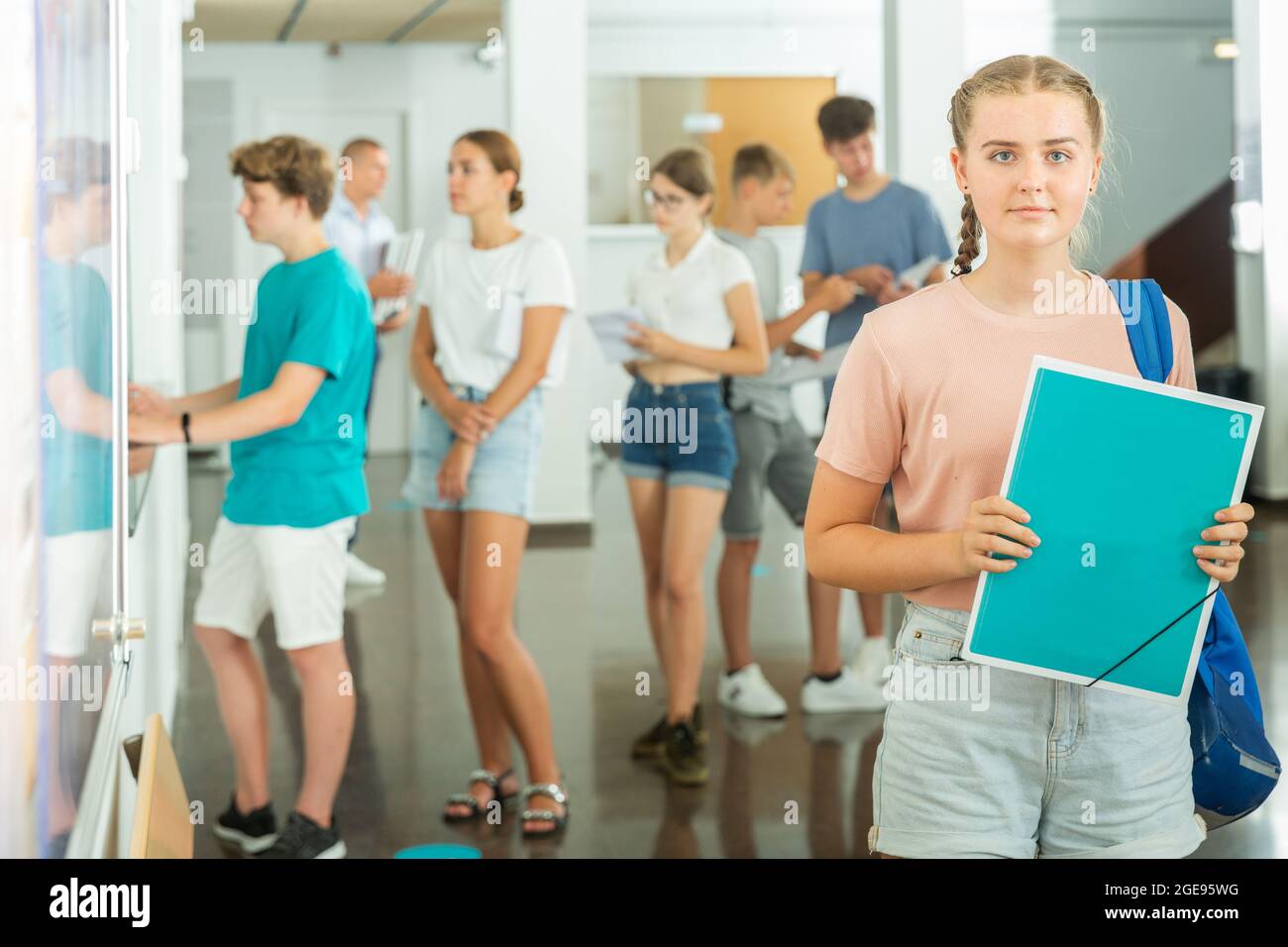 Teenage girl standing in school's hallway. Group of young students ...