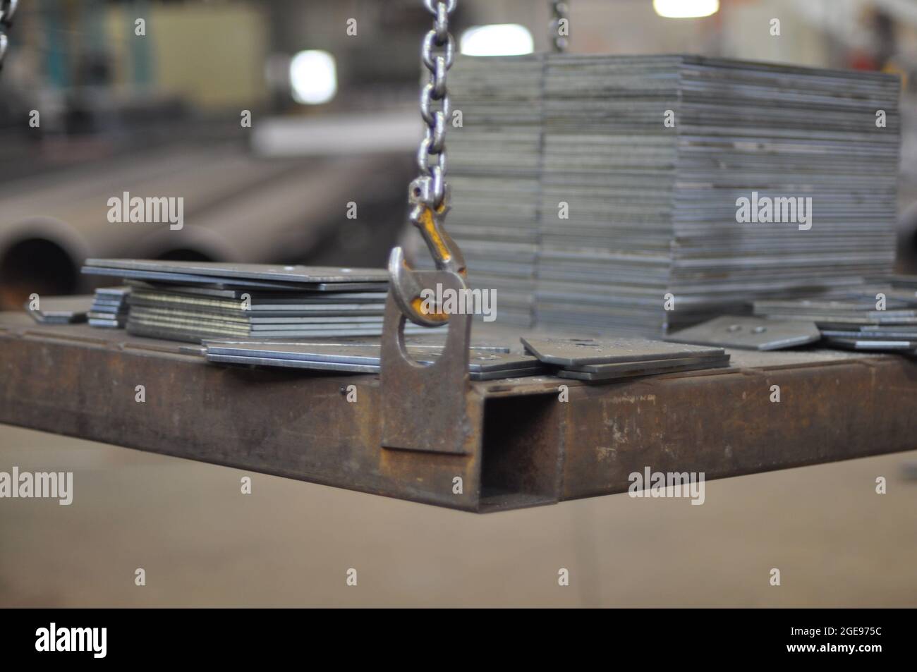 Crane hook. Lifting and moving a metal pallet with parts in a workshop ...