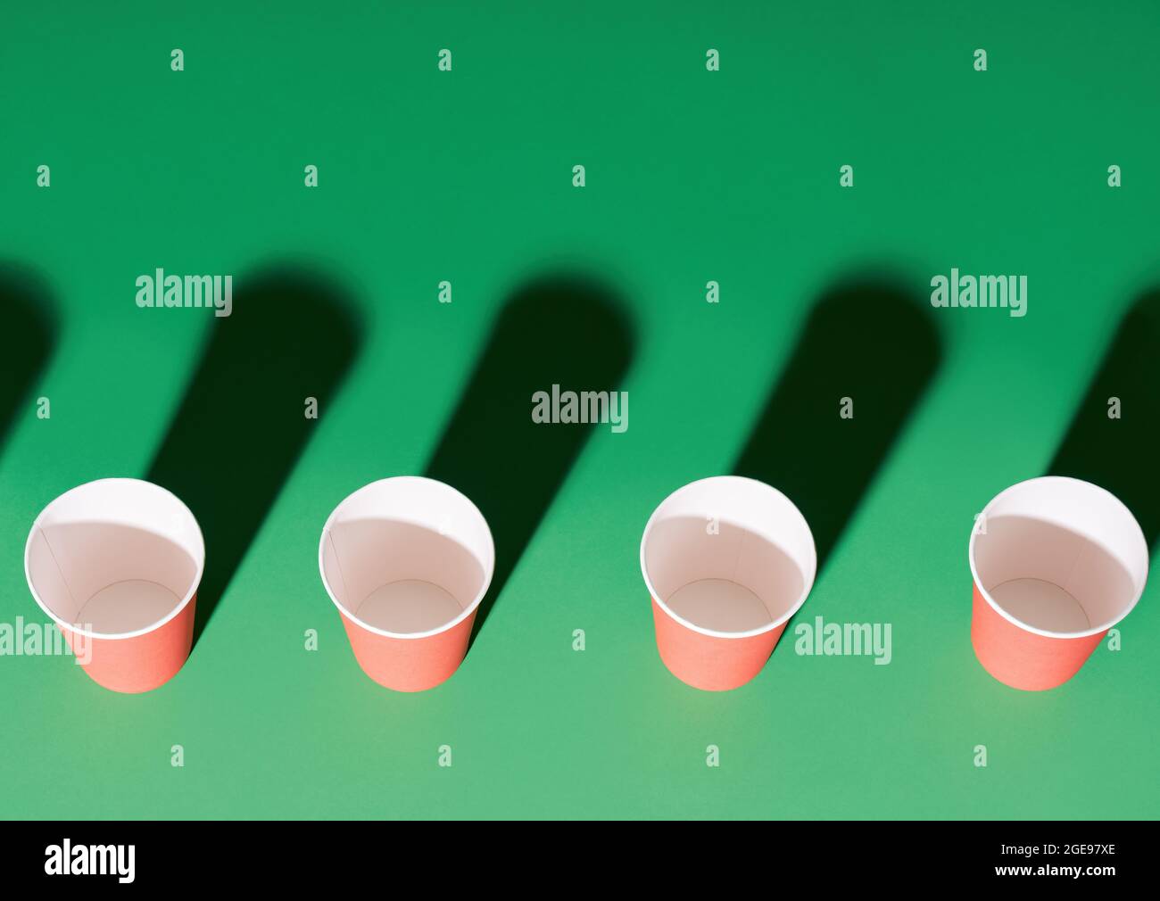 Top view of red paper cup in row on green background with shadows ...