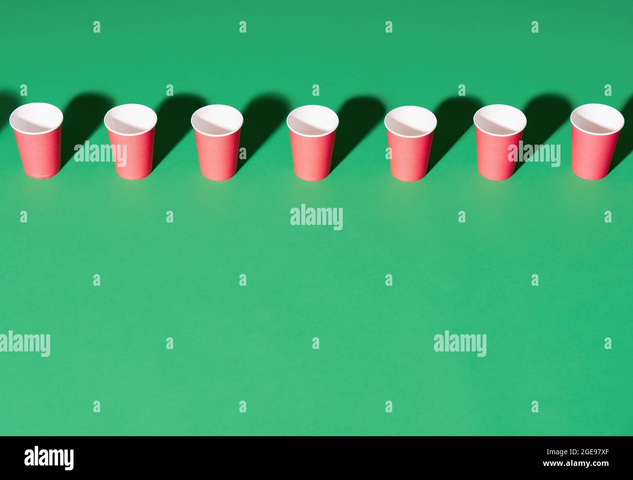 Row of red paper cup on green background with copy space. creative ...