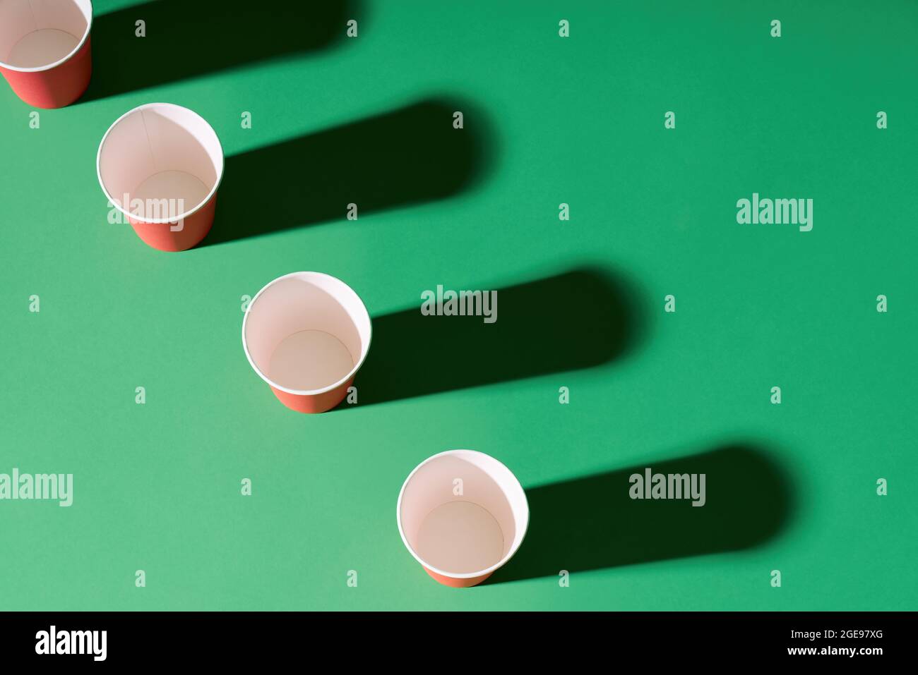 Top view of red paper cup in row on green background with shadows ...